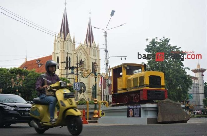 Pengendara melintas Lokomotif Tebu (Lori) di depan patung Chairil Anwar ...